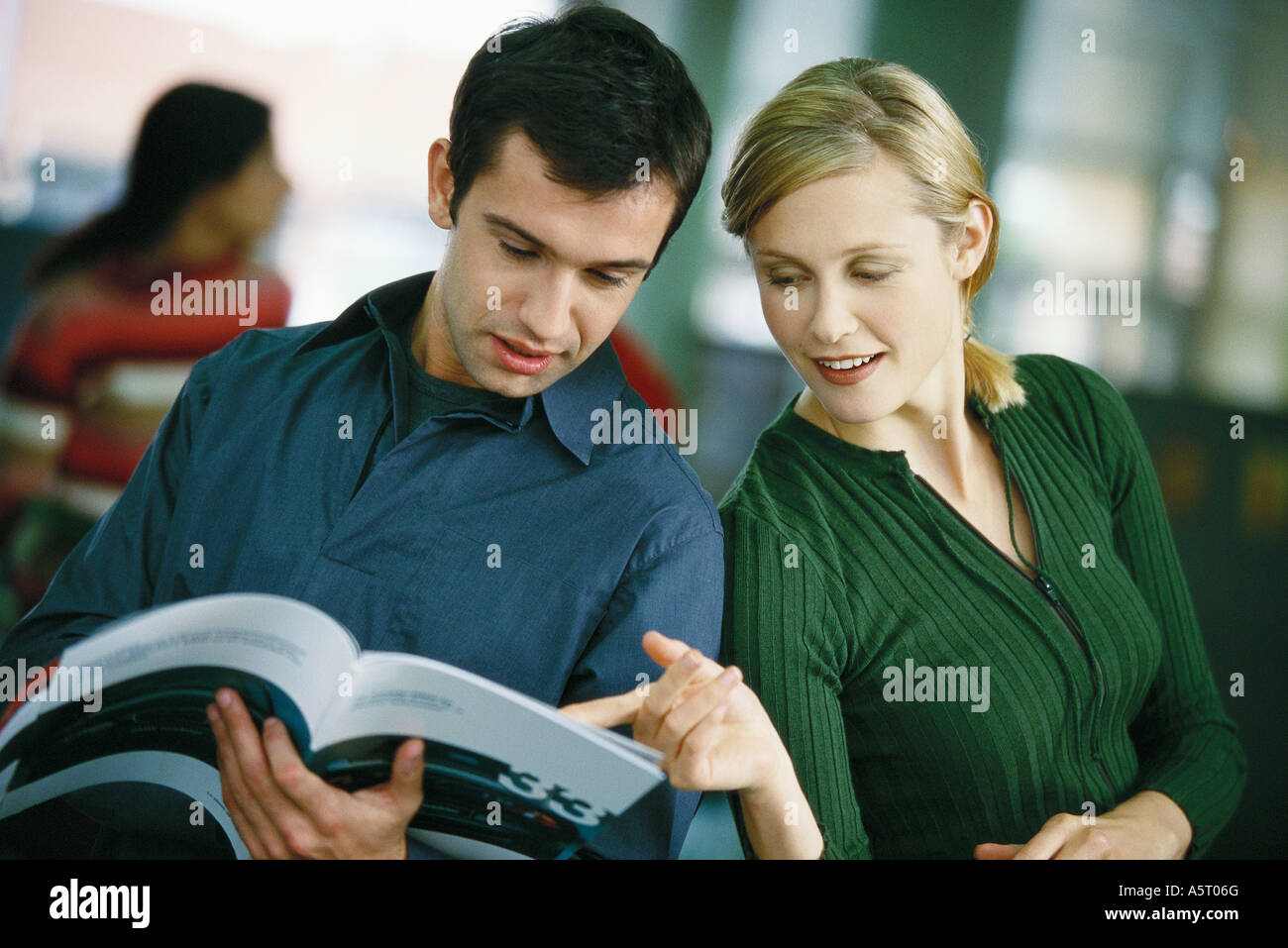 Man holding brochure, woman looking over his shoulder, pointing to page ...