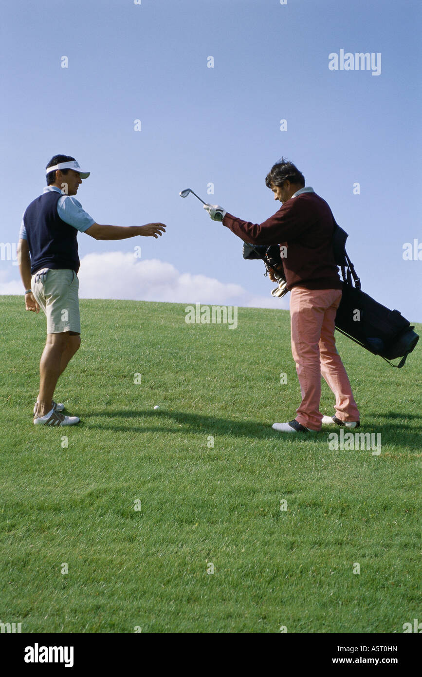 Caddy handing golfer golf club Stock Photo - Alamy