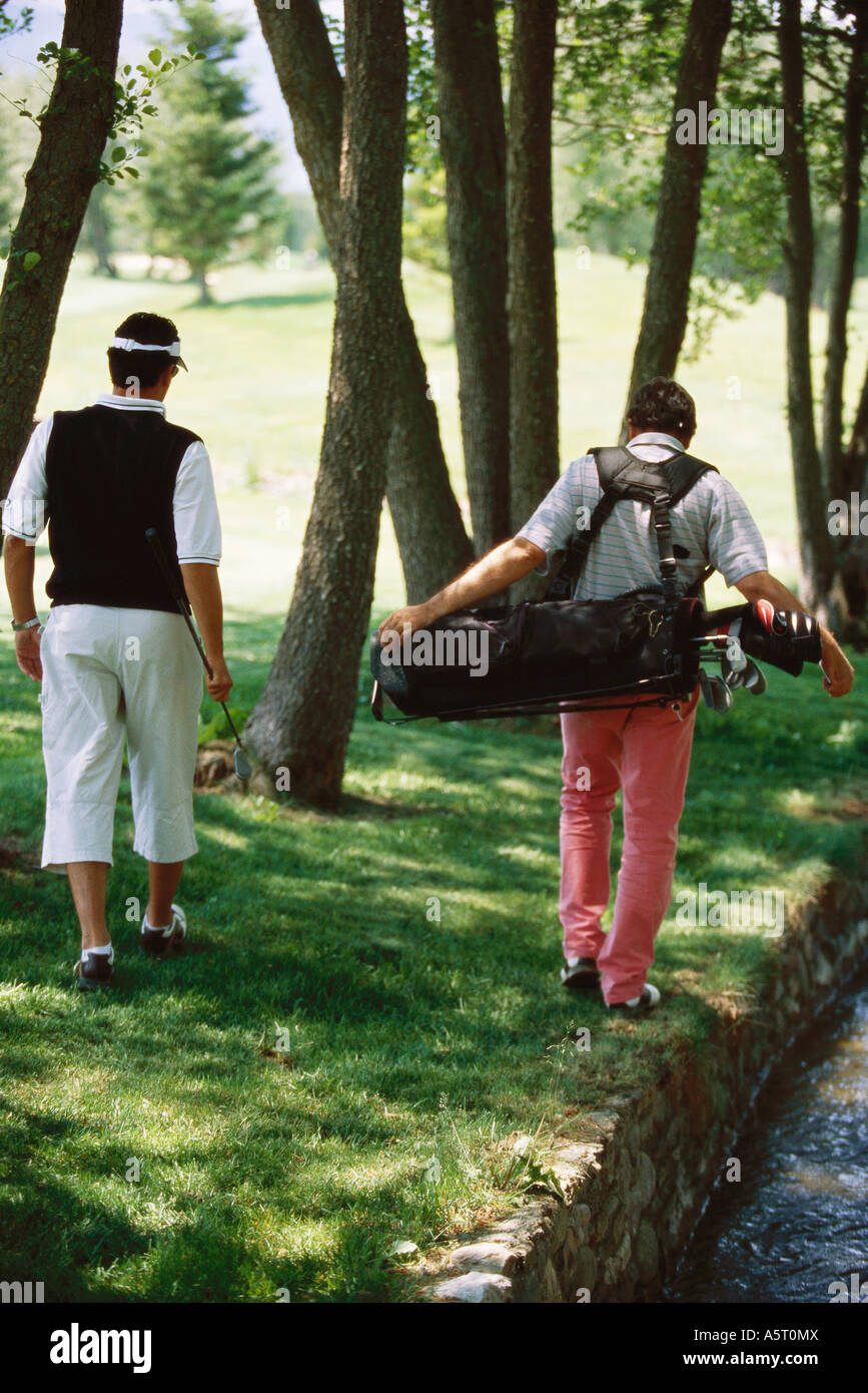 Golfers looking for ball under trees, rear view Stock Photo - Alamy