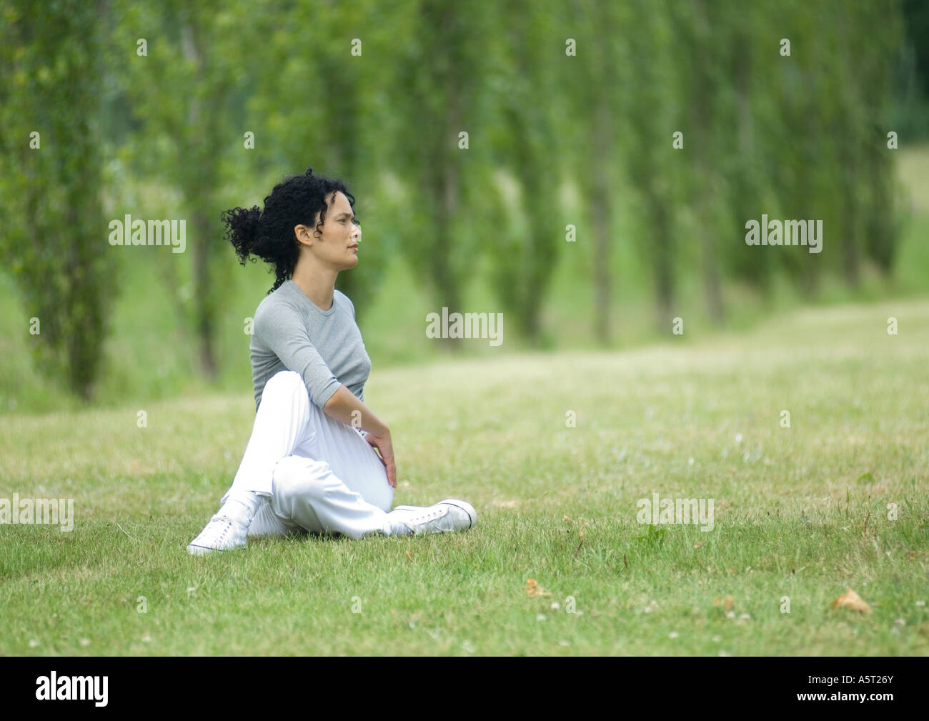 Young woman stretching on grass Stock Photo - Alamy