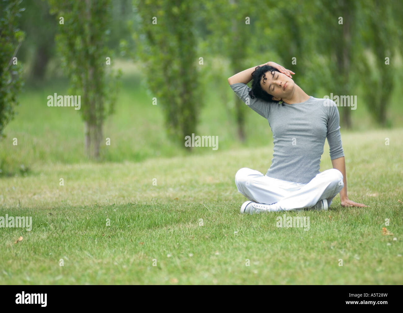 Young woman stretching on grass Stock Photo - Alamy
