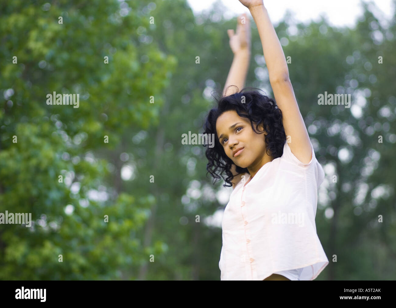 Young woman standing with arms raised Stock Photo - Alamy