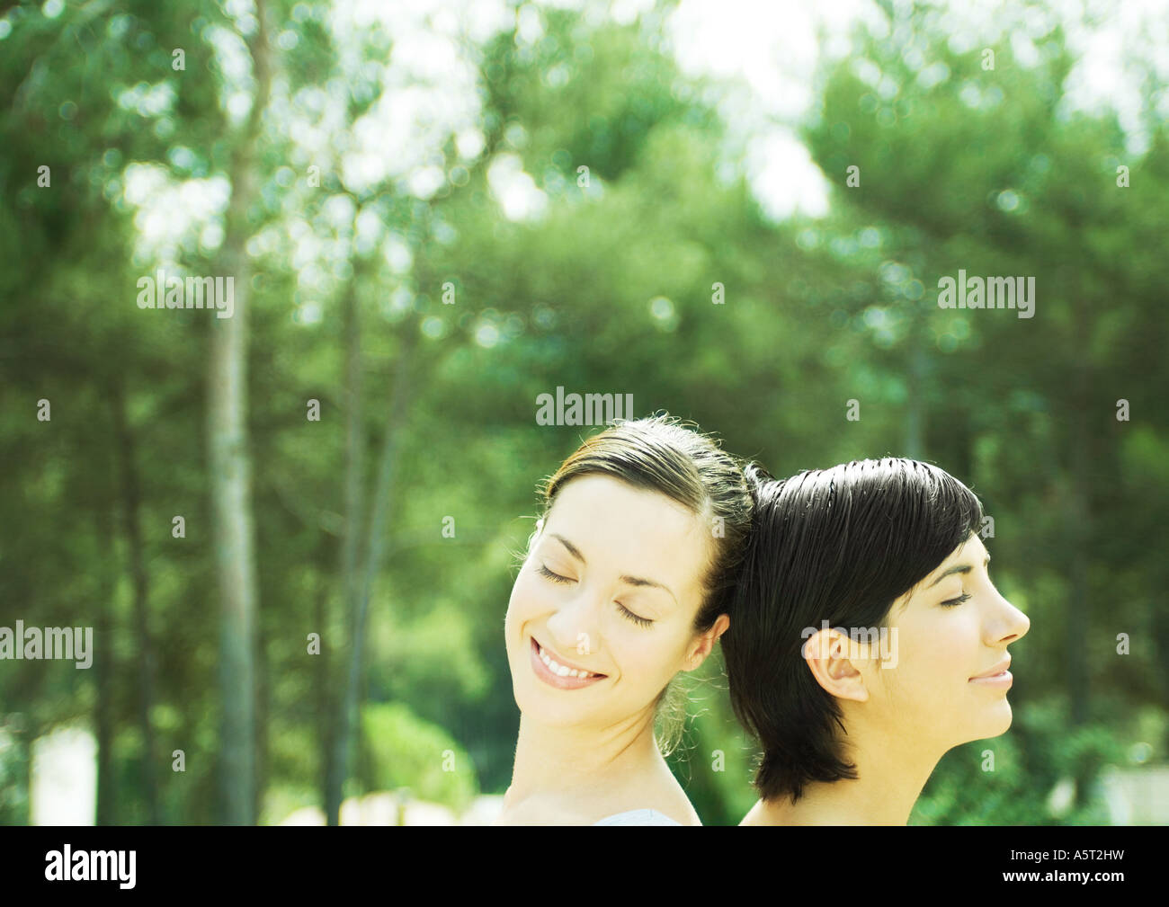 Two women sitting back to back, cropped view of heads Stock Photo - Alamy
