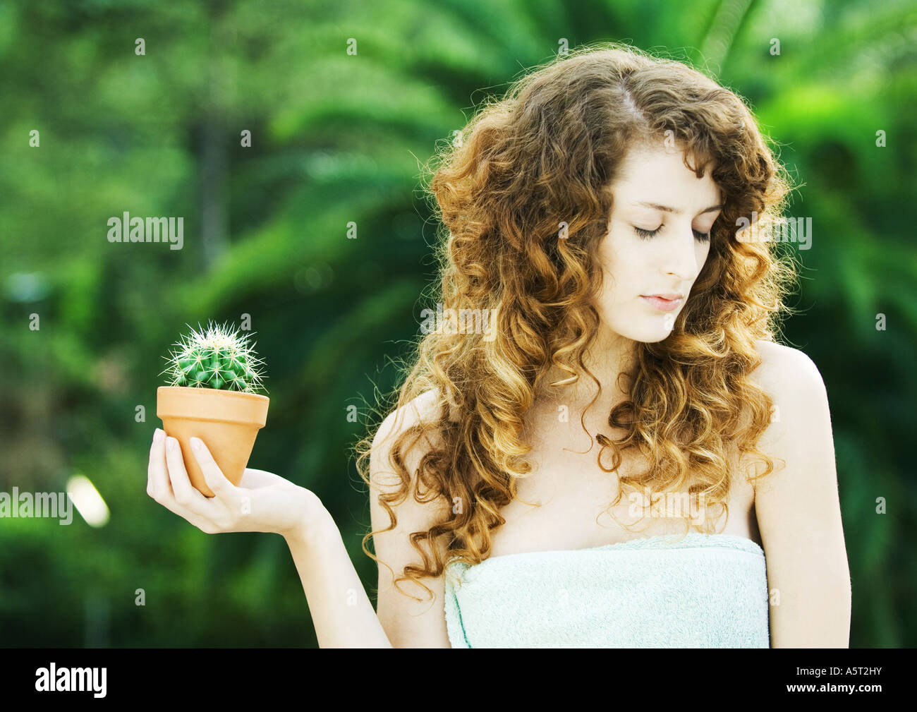 Woman holding cactus in palm, looking away Stock Photo - Alamy
