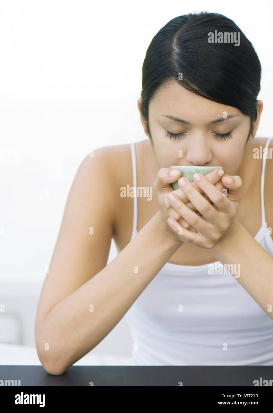Woman holding up cup to face, eyes closed Stock Photo - Alamy