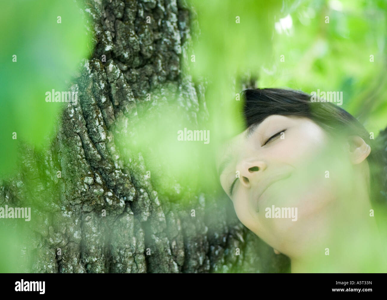 Woman leaning against tree Stock Photo - Alamy