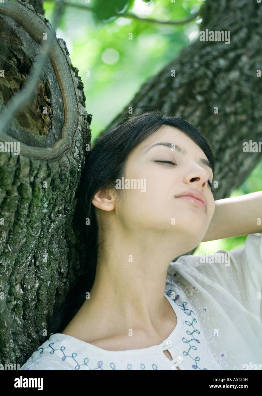 Woman leaning against tree Stock Photo - Alamy