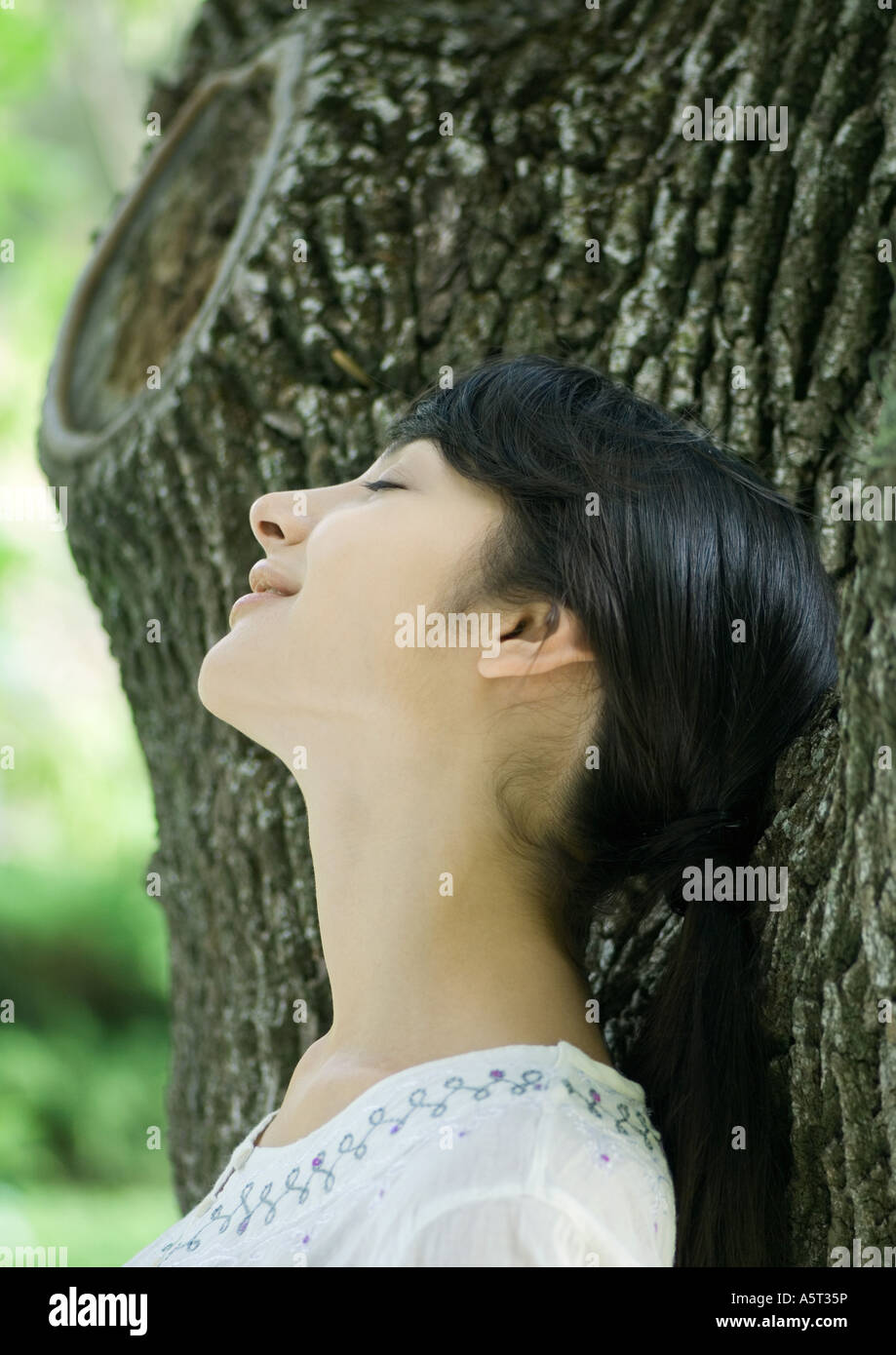 Woman leaning against tree Stock Photo - Alamy