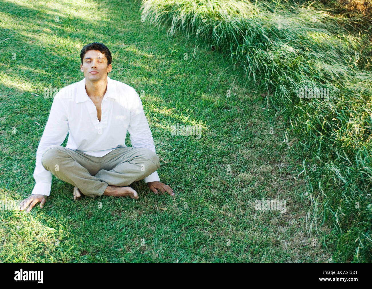 Man sitting indian style on grass, eyes closed Stock Photo - Alamy