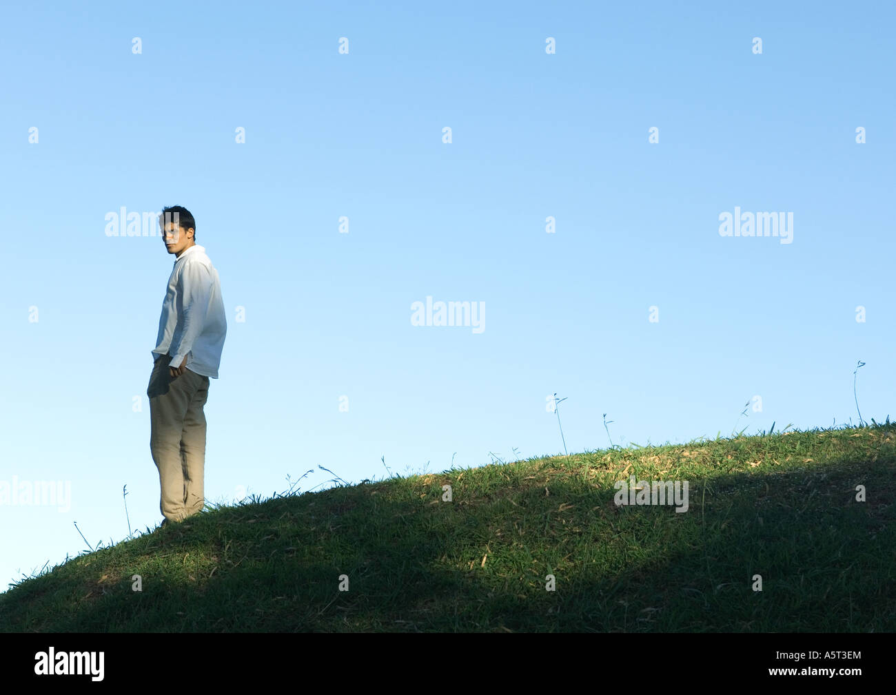 Man standing on hill, looking over shoulder toward camera Stock Photo ...