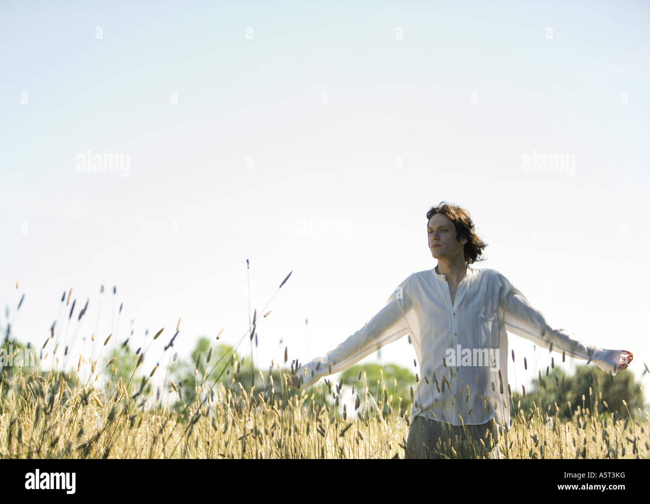Man standing in field with arms out Stock Photo - Alamy