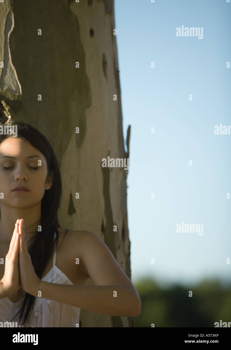 Woman standing in prayer position near tree Stock Photo - Alamy