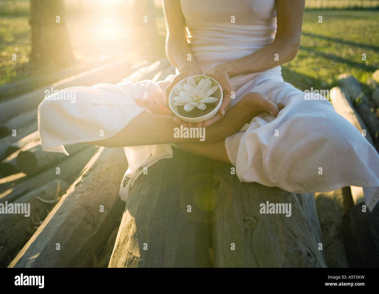 Woman sitting in lotus position, holding lotus flower Stock Photo - Alamy