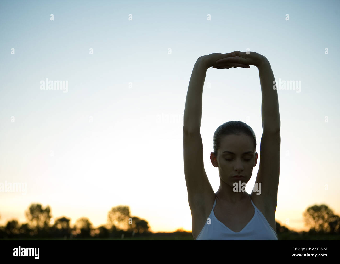Woman stretching arms over head, backlit Stock Photo - Alamy