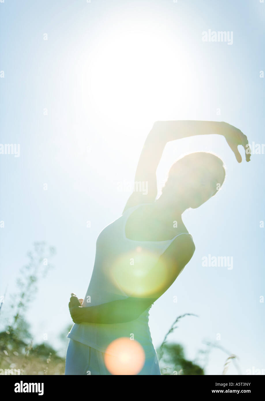 Woman standing, stretching arm over head, in sunshine Stock Photo - Alamy