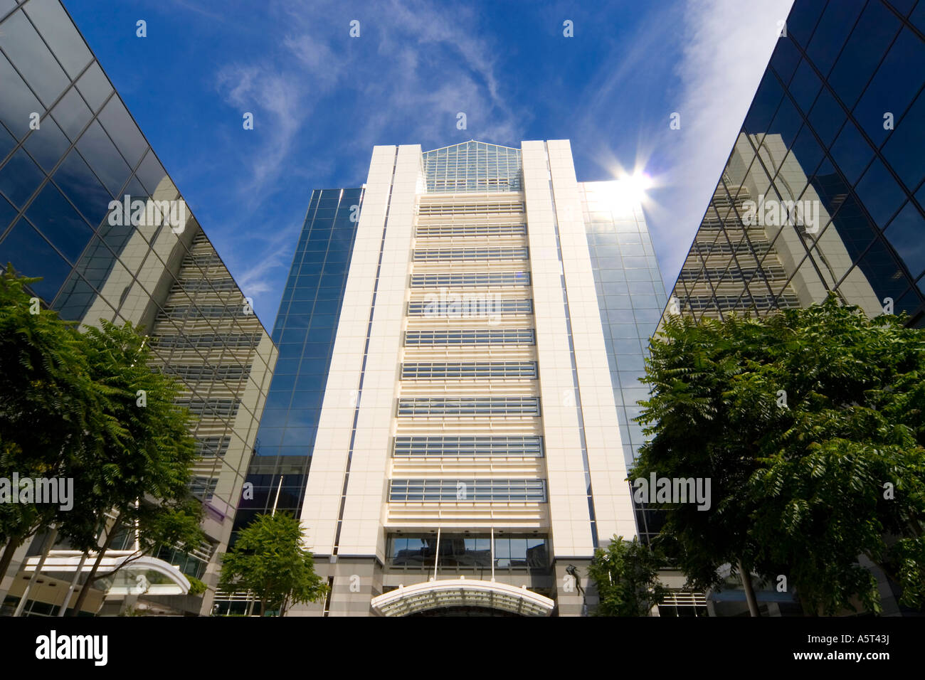 Glass fronted skyscrapers reach up into a bright blue sky with a few ...