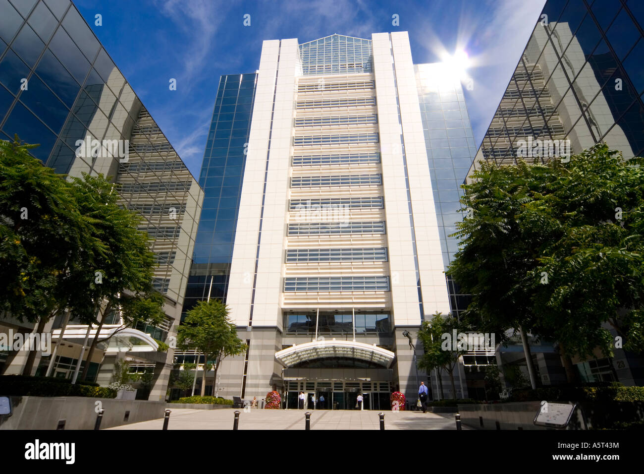 Glass fronted skyscrapers reach up into a bright blue sky with a few ...