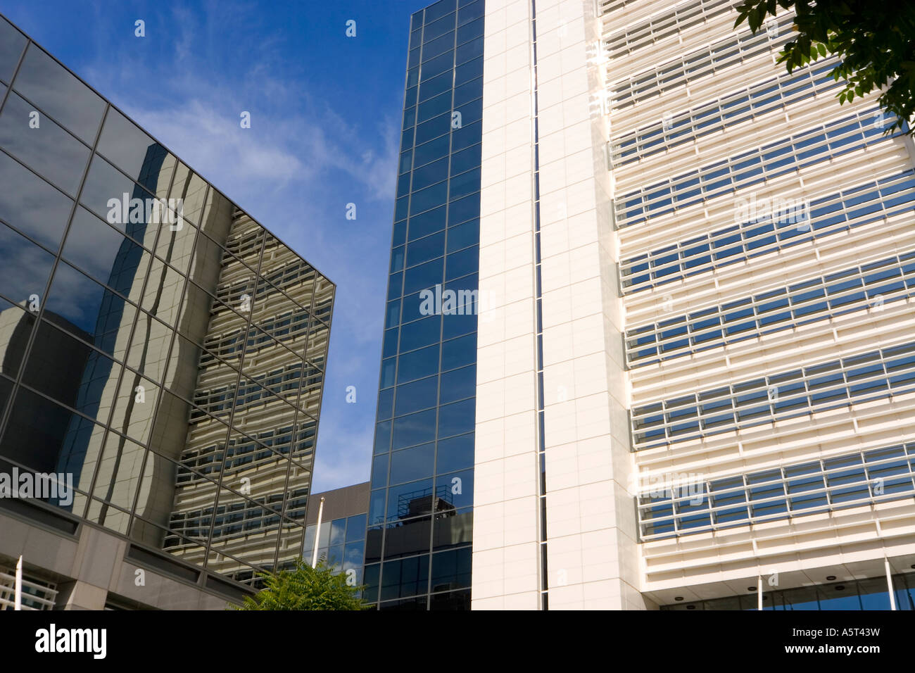 A glass fronted office building with the reflections of surrounding ...