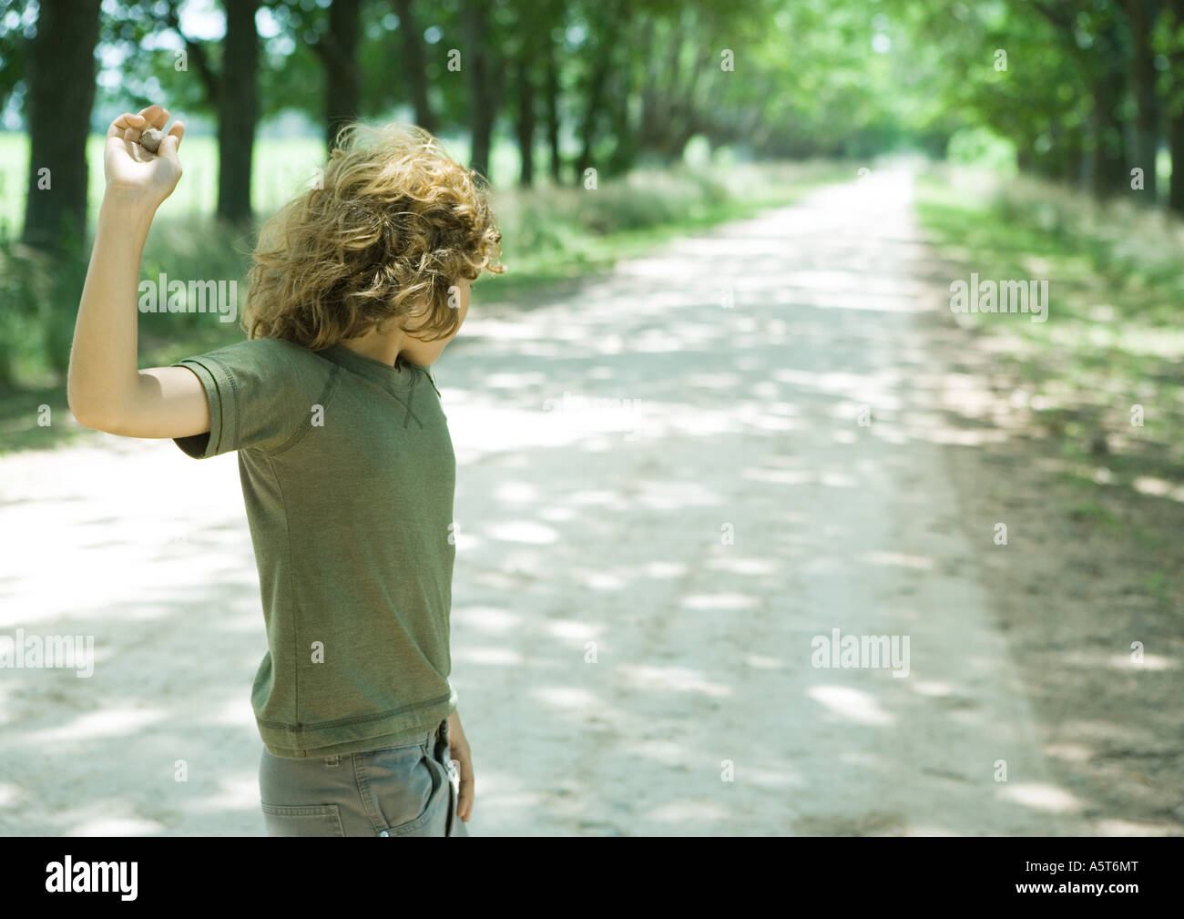 Boy standing in middle of dirt road, throwing pebbles Stock Photo - Alamy