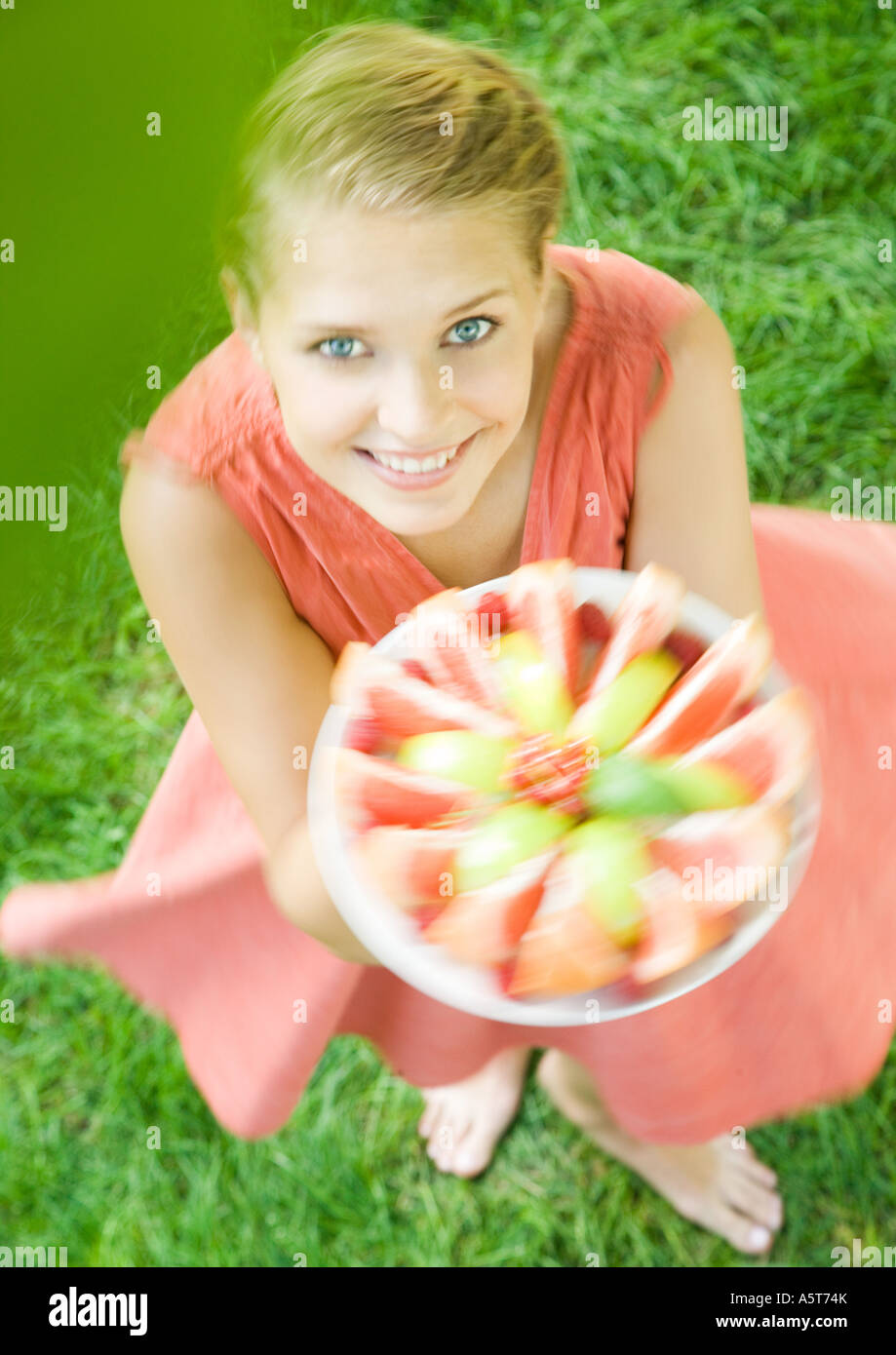 Woman holding up plate full of fruit slices and spinning around, high ...