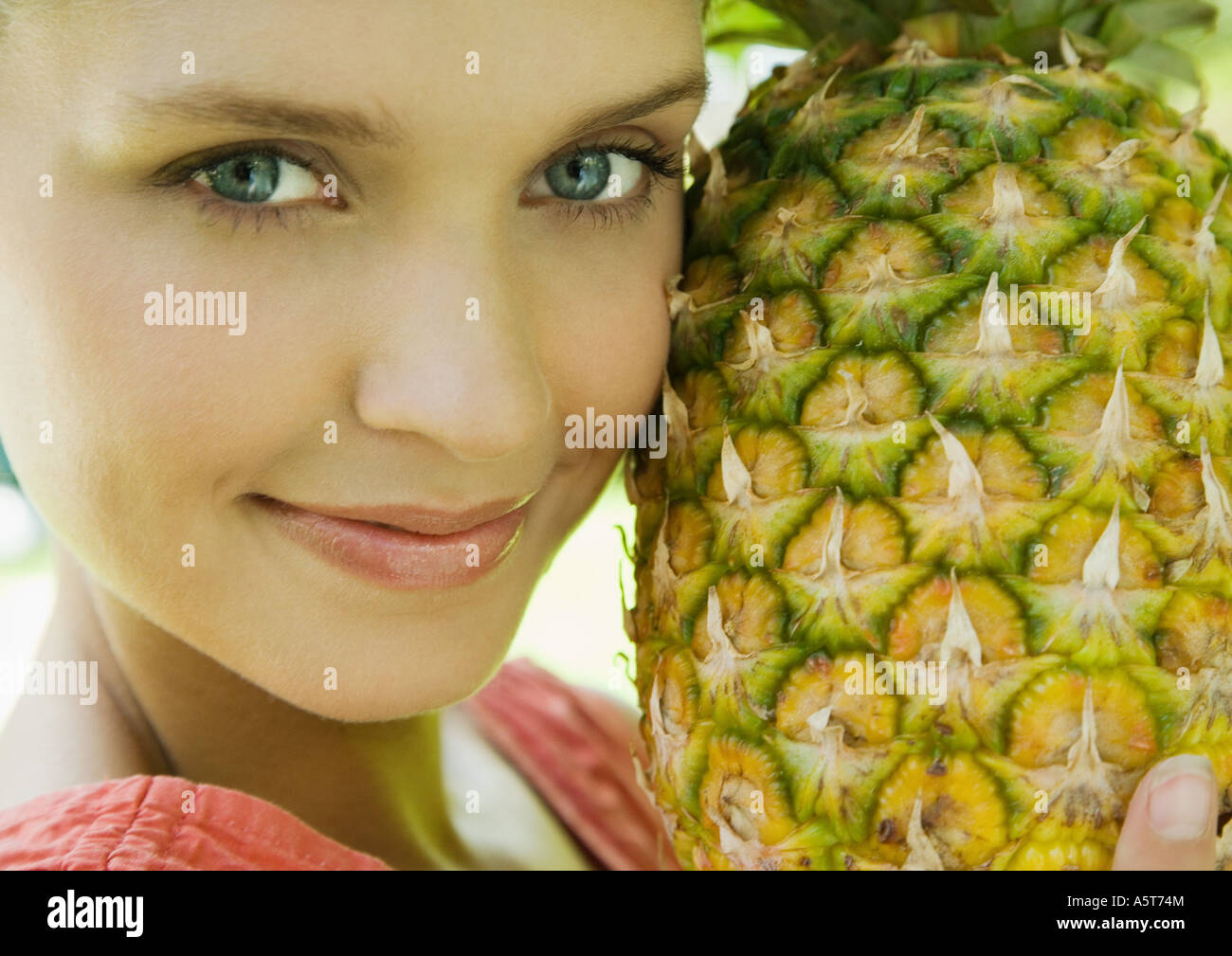 Woman holding up pineapple to face Stock Photo - Alamy
