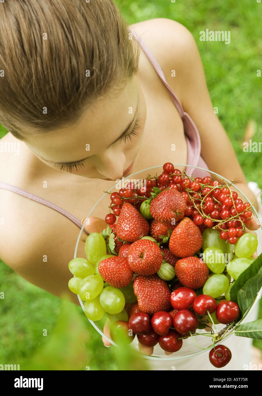 Young woman holding up bowl of fruit Stock Photo - Alamy