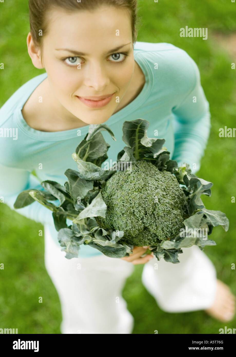 Young woman holding up broccoli Stock Photo - Alamy