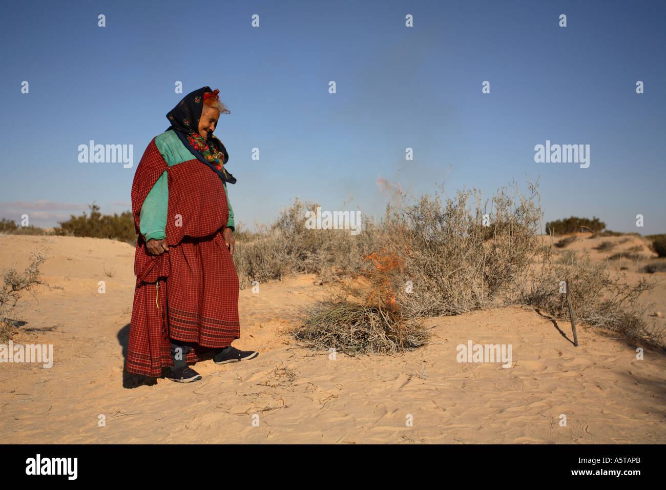 Horizontal portrait of elderly nomadic berber woman lighting fire and ...