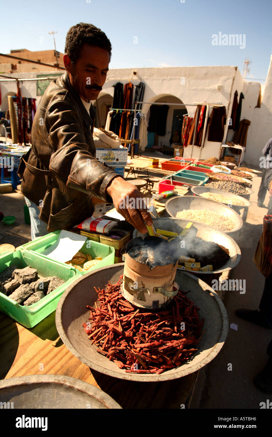 Vertical portrait of spice stall vendor in Douz outdoor market putting ...