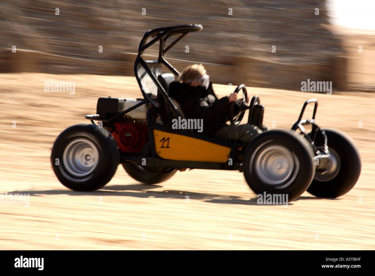 Panned horizontal portrait of boy in go kart driving at speed, showing ...
