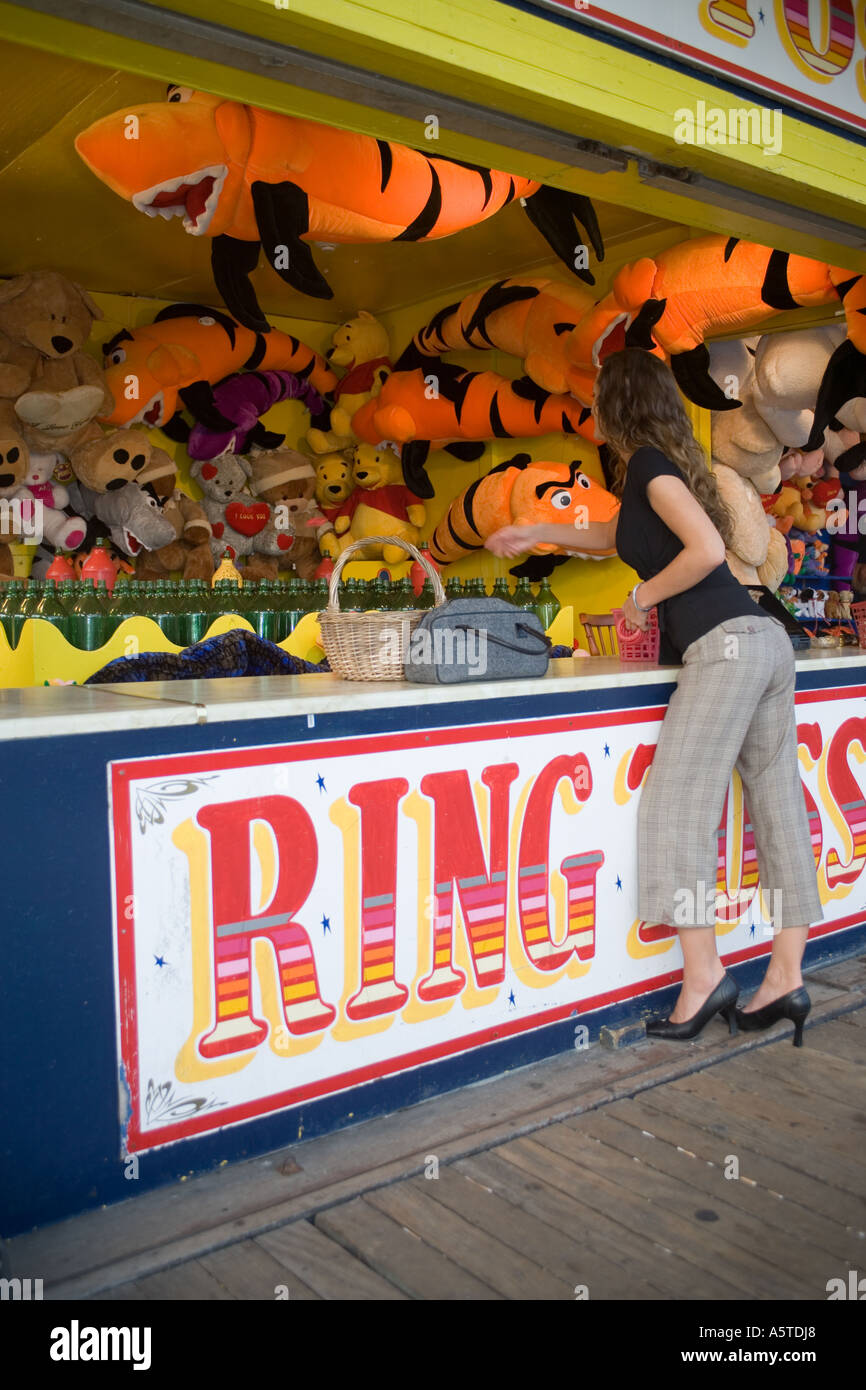 Pretty girl throwing hoops on a stall at the fun fair on South Pier ...