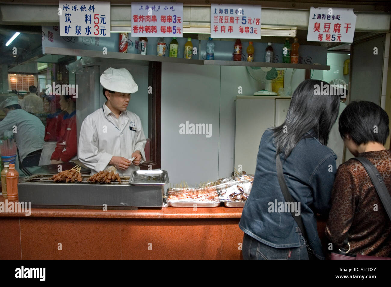 Young Chinese shop assistant serving two young chinese females at a ...
