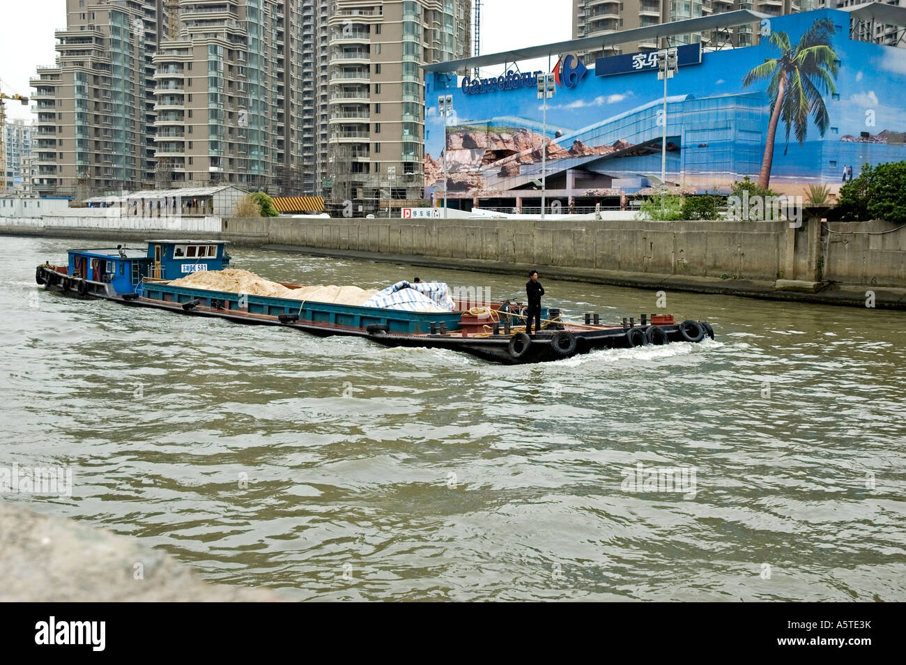 Barge carrying construction materials with crewman standing at front ...