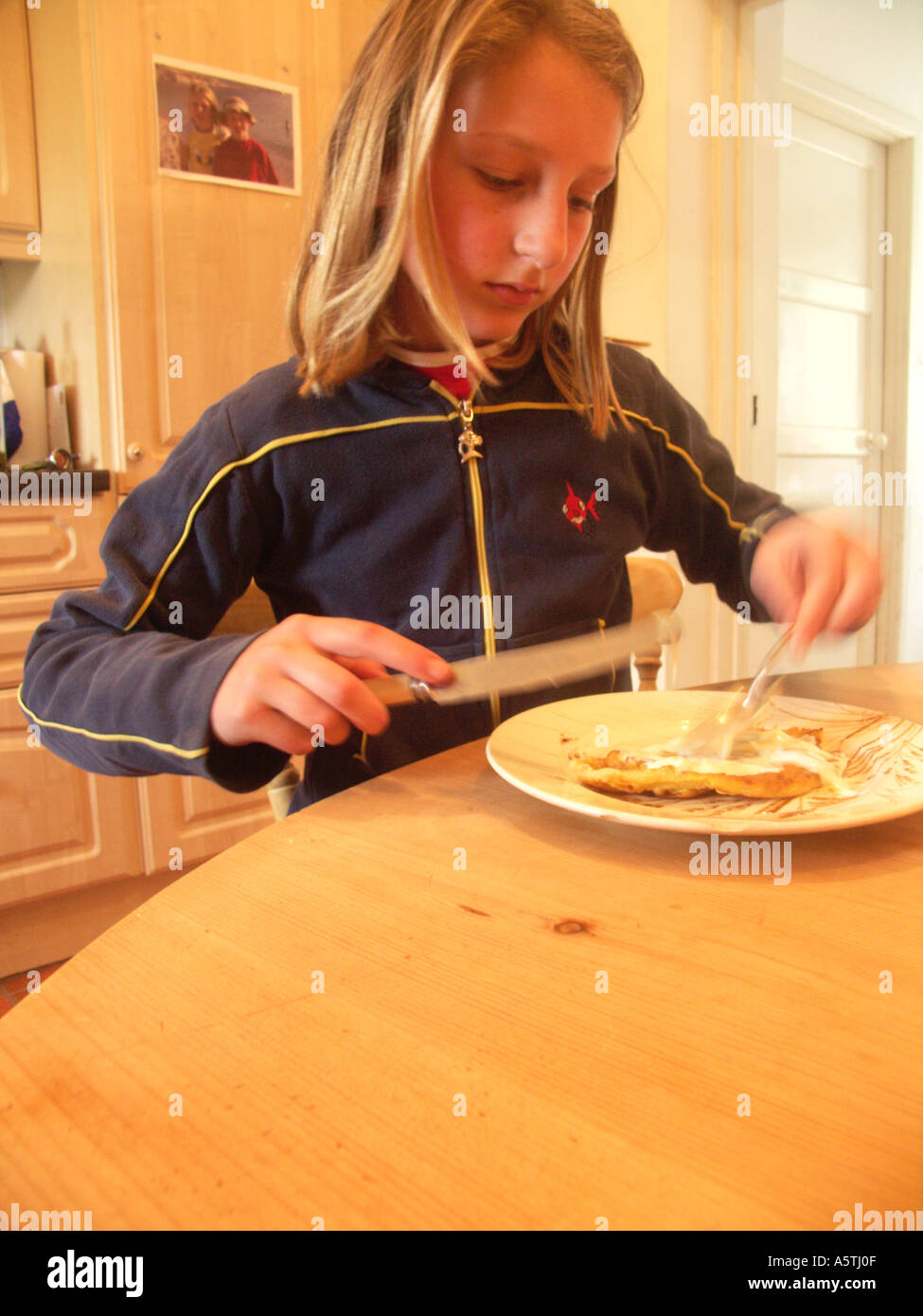 Girl eating a pancake at kitchen table Stock Photo - Alamy