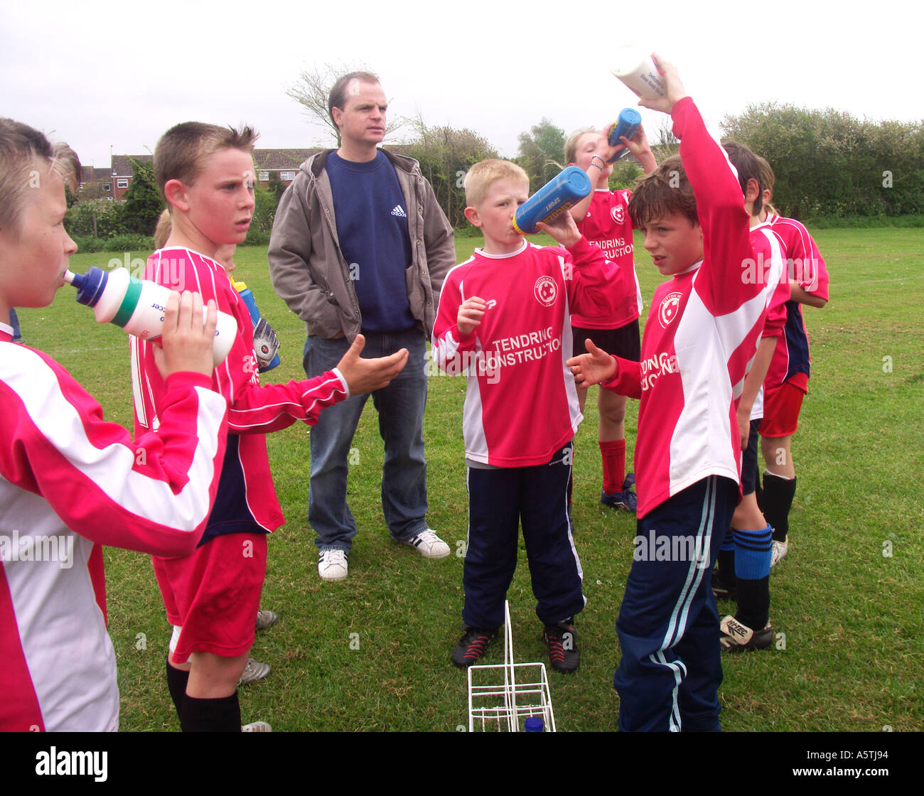 Children s football team at half time team talk with coach drinking ...