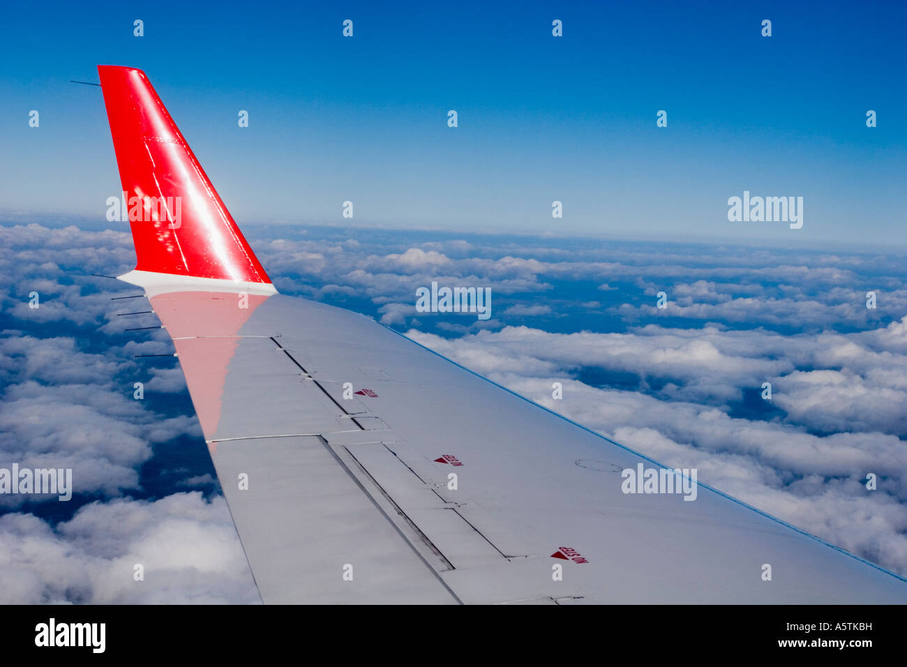 Wing of jet plane above clouds seen while flying Stock Photo - Alamy