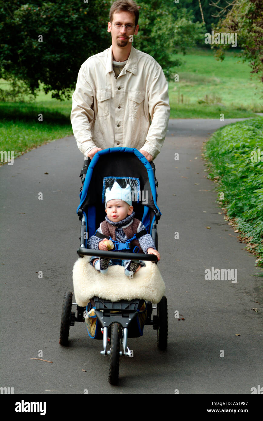 MR father with his baby boy in a baby buggy having a walk Stock Photo ...