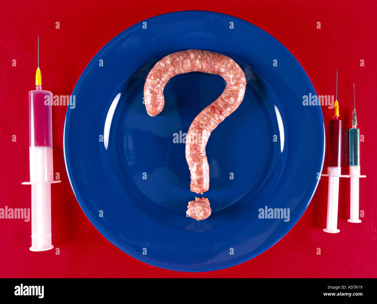 blue plate with sausage in form of question mark and three syringes ...