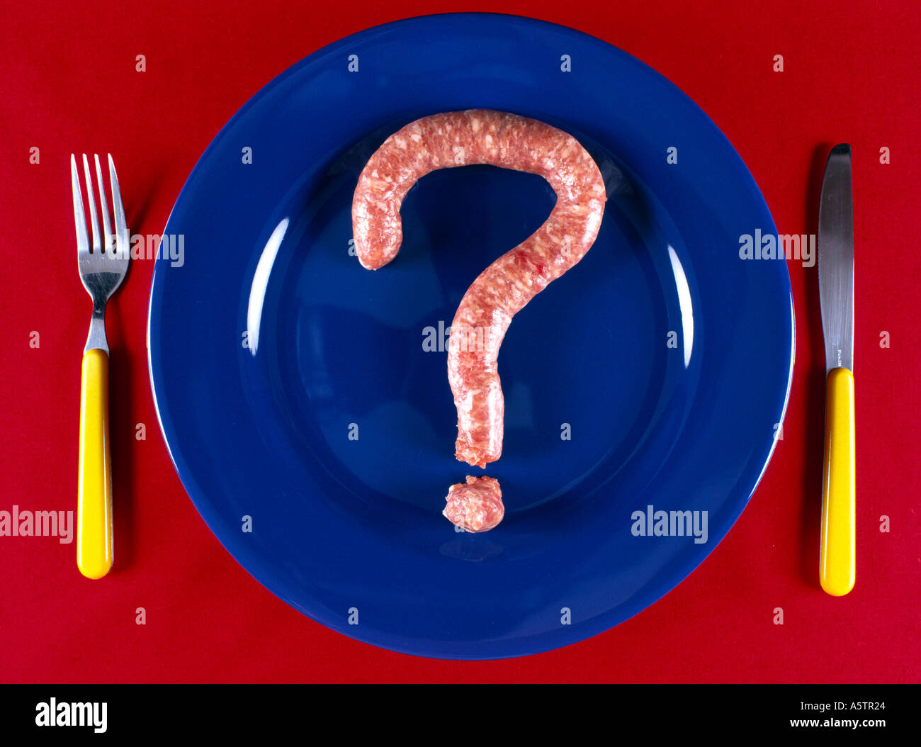 cutlery and blue plate with sausage in form of question mark Stock ...