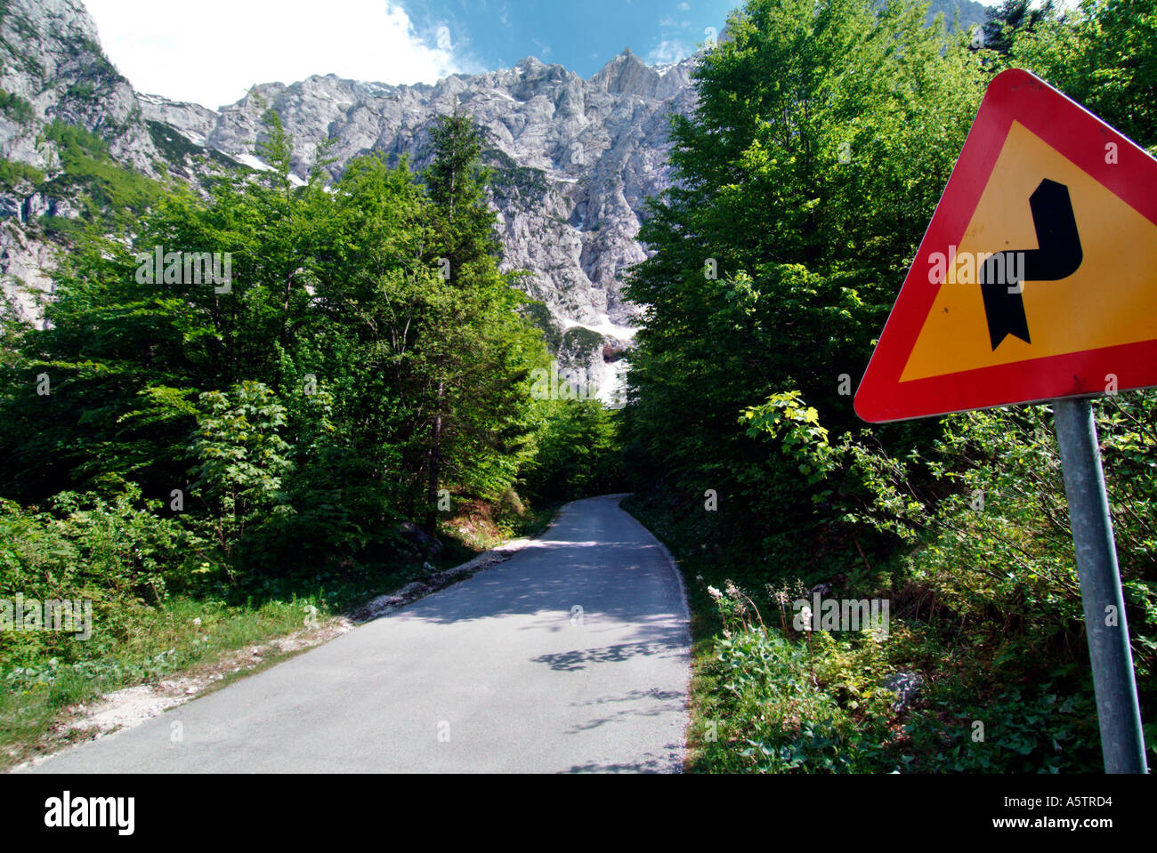 warning sign for winding road in the mountains Stock Photo - Alamy