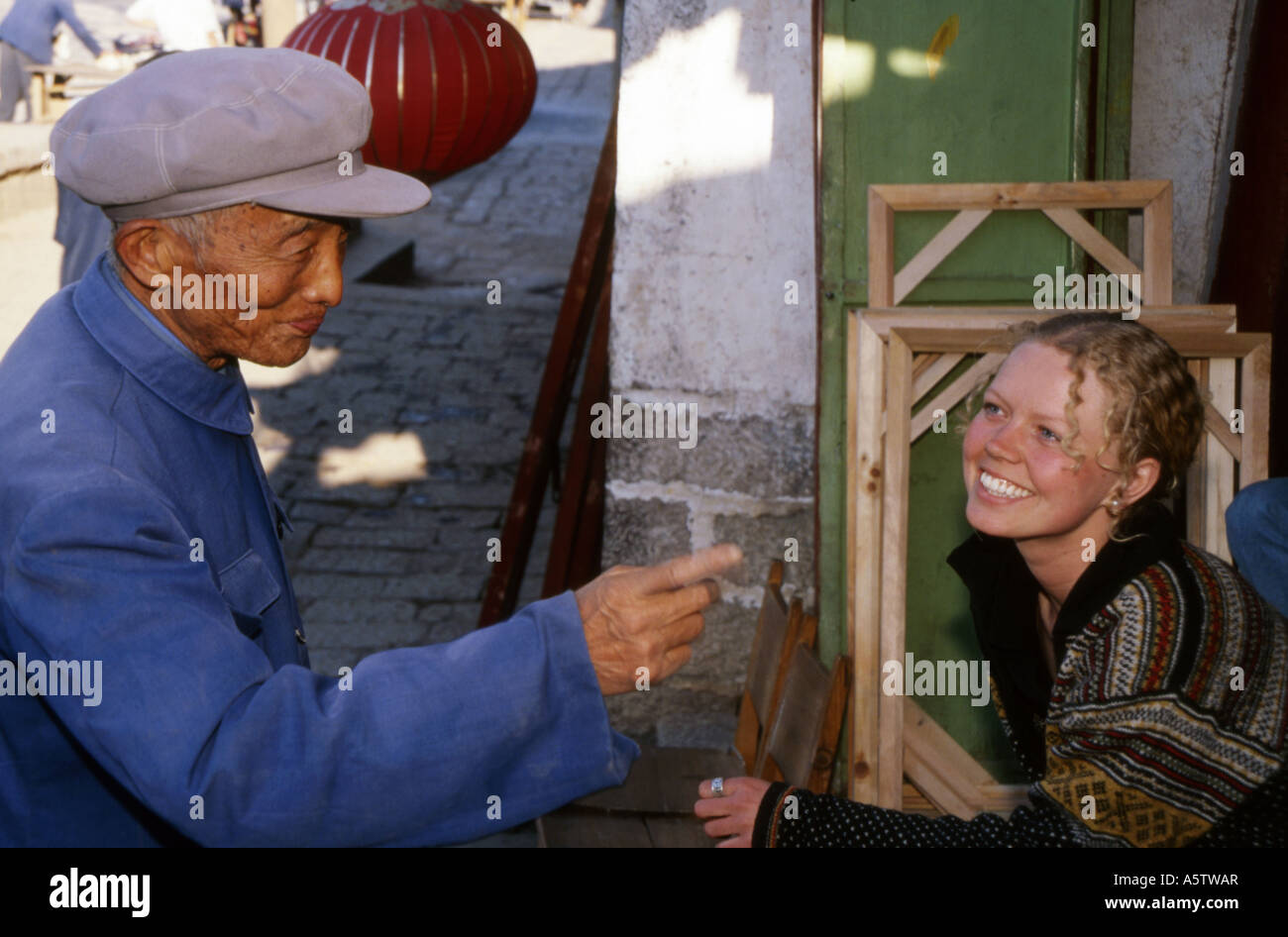 Laughing,young pretty female Western tourist talking to elderly local ...