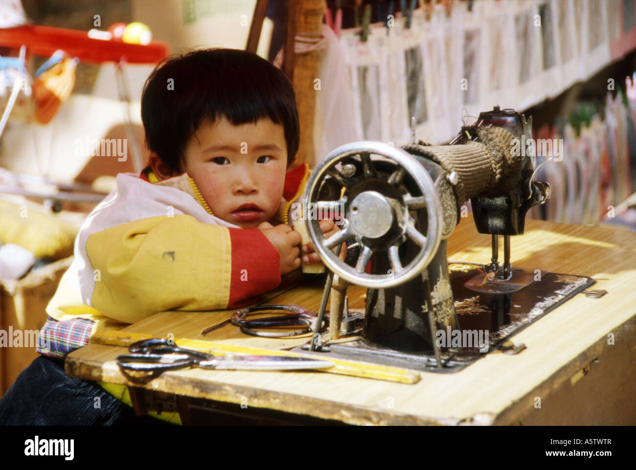 Young local boy next to old sewing machine on top of table at roadside ...