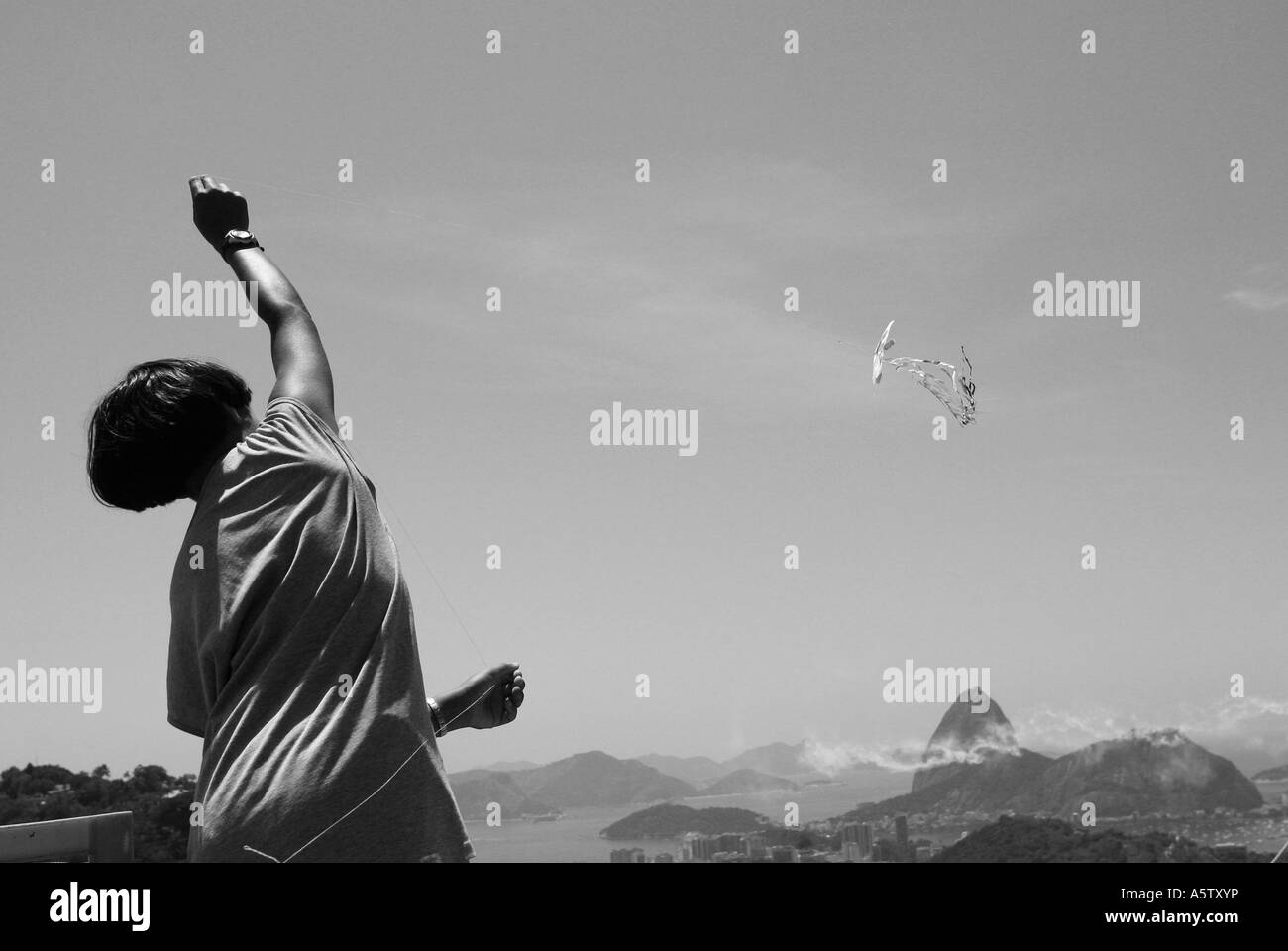 Portrait of young boy flying his kite over shantytown favela, Rio de ...