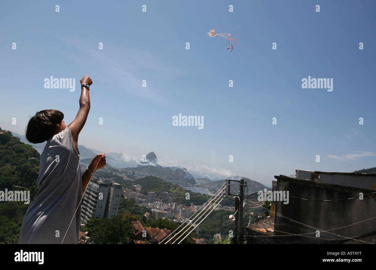 Portrait of young boy flying his kite over shantytown favela, Rio de ...