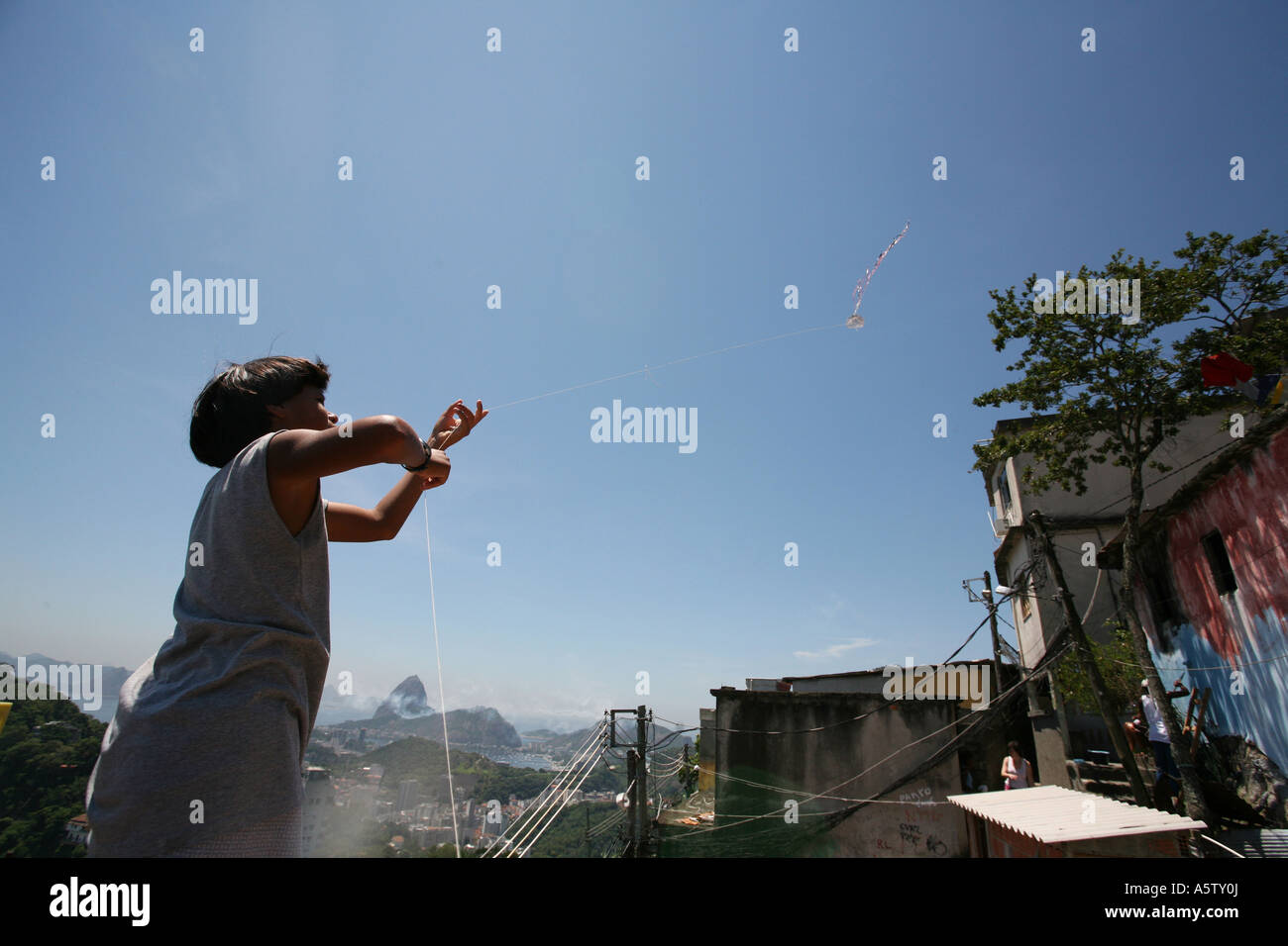 Portrait of young boy flying his kite over shantytown favela, Rio de ...