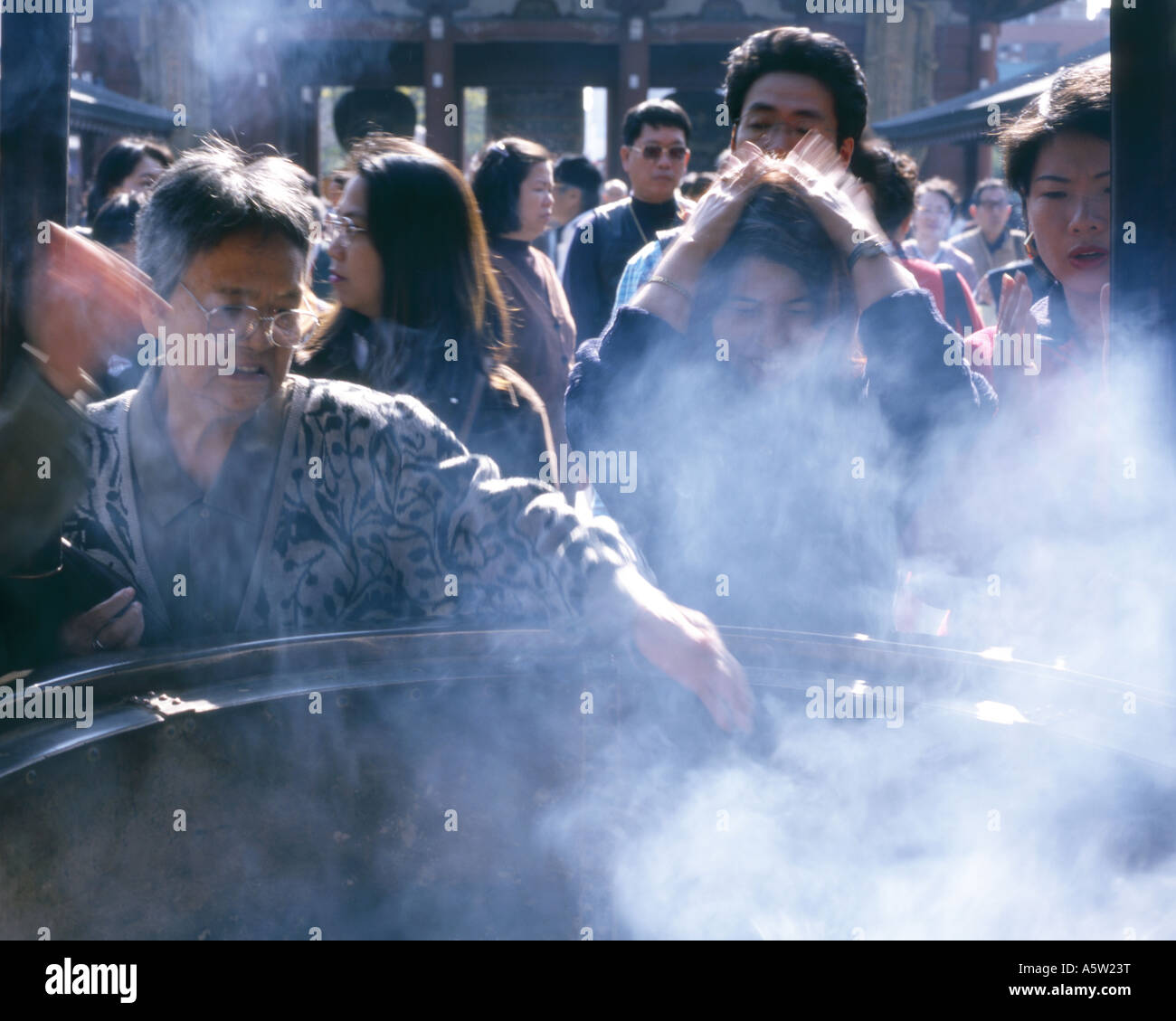 Smoke from incense sticks envelops worshipers at the giant cauldron ...