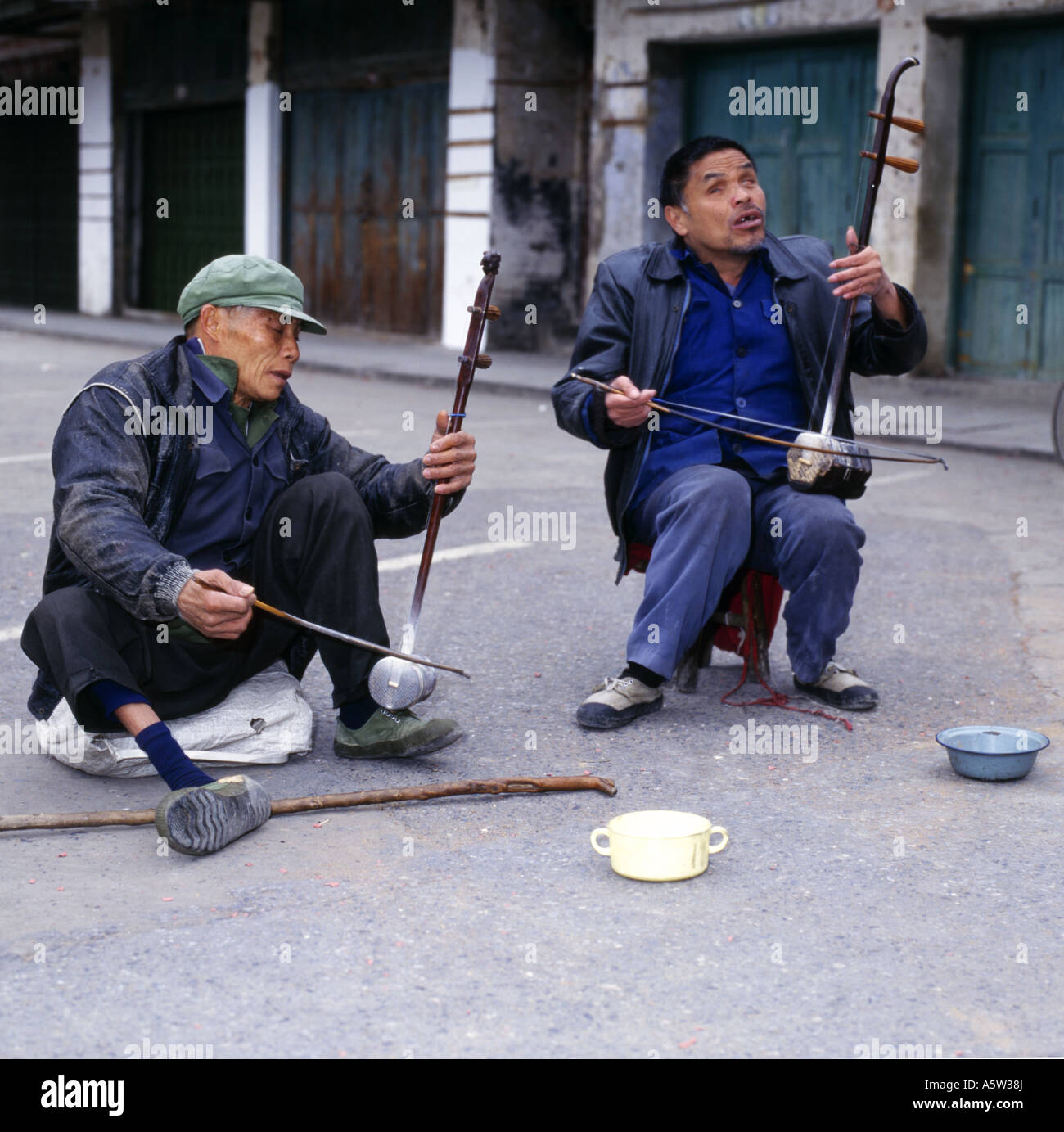 Two blind musicians play their instruments in the street,awaiting ...