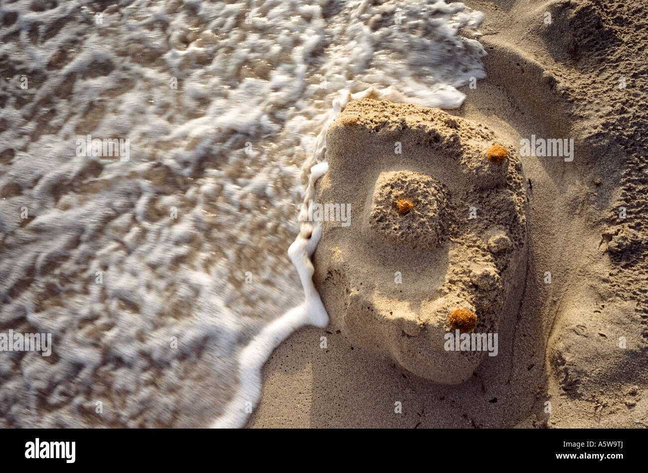 Sandcastle being washed away by sea Stock Photo - Alamy