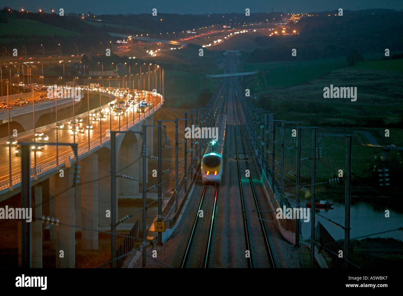 Eurostar train crossing the River Medway at night close to M2 Motorway ...