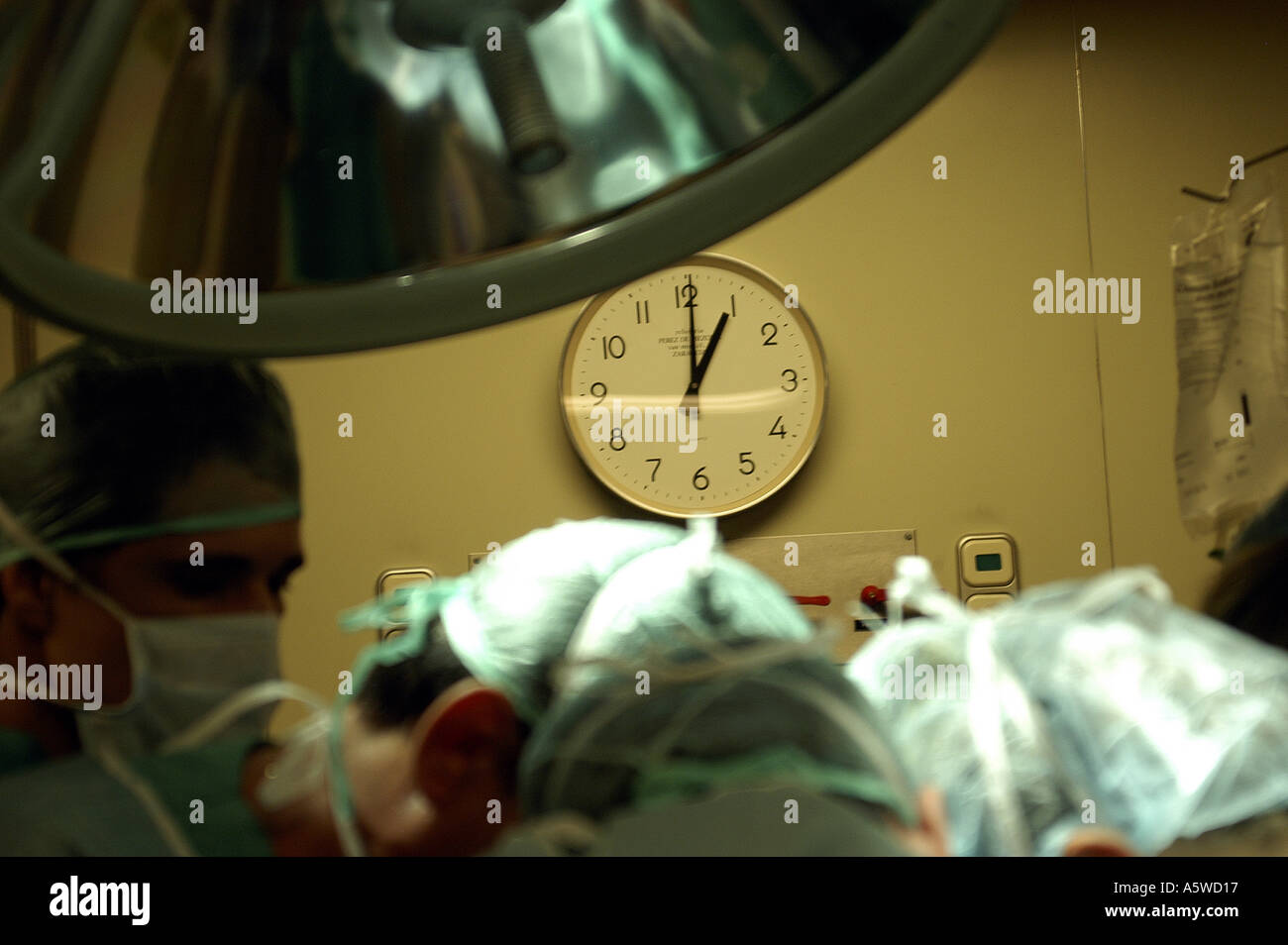Surgeons practicing surgery in an operating room and a wall clock ...